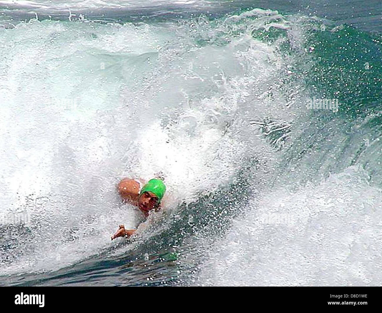 Ocean waves crash against the shore as surfers ride them, showcasing ...