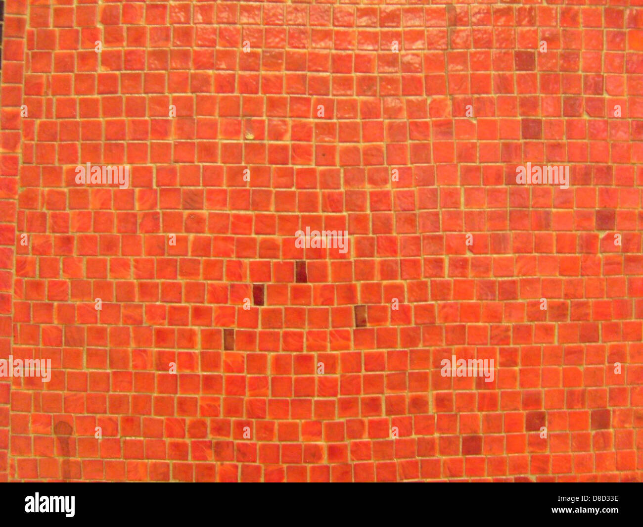 A vibrant orange mosaic wall made of small, colorful tiles arranged in ...