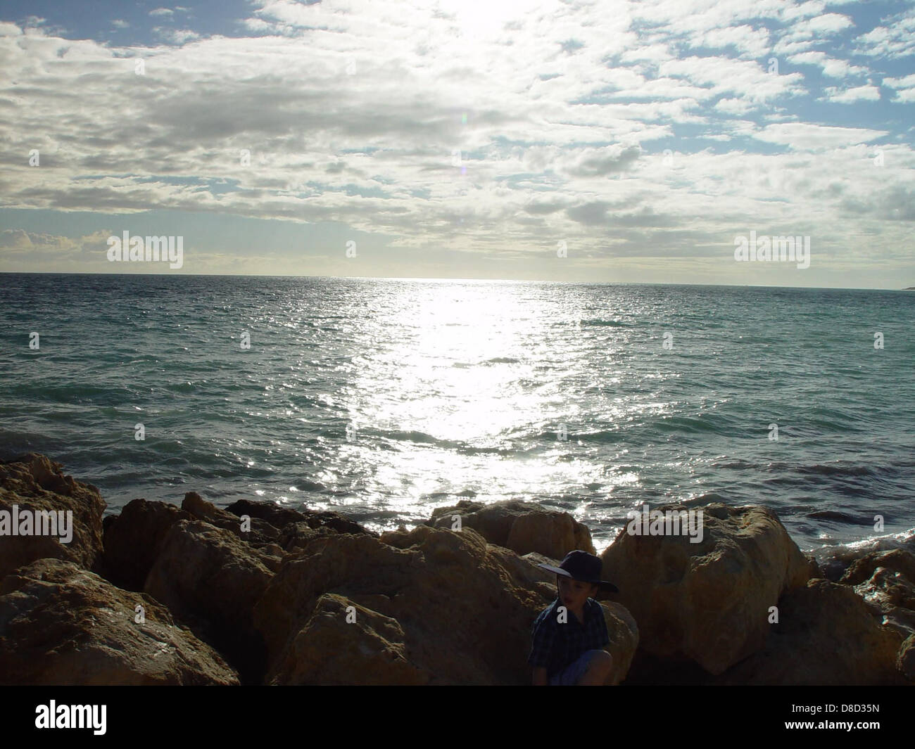 The sun rises over the Pacific Ocean, casting golden light on rocks ...