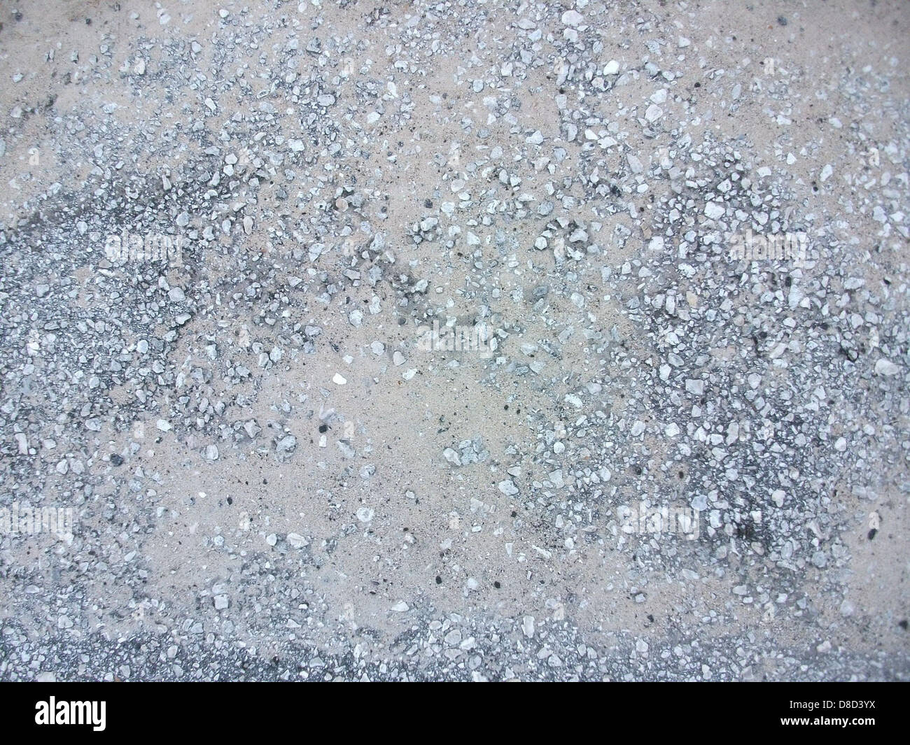 This image shows a pavement covered with a thin layer of sand. The ...