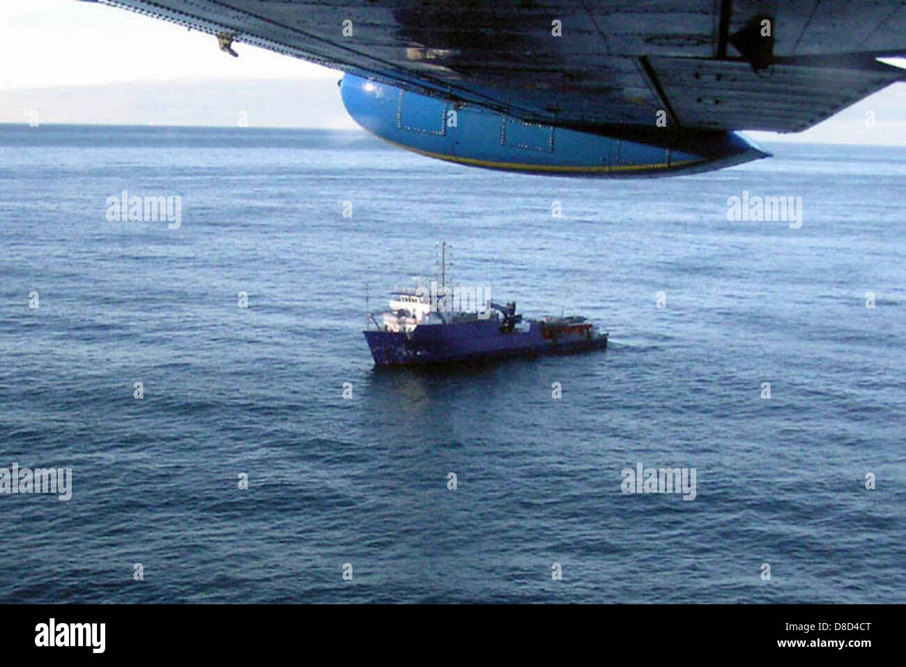 Plane flying over ship on ocean Stock Photo - Alamy