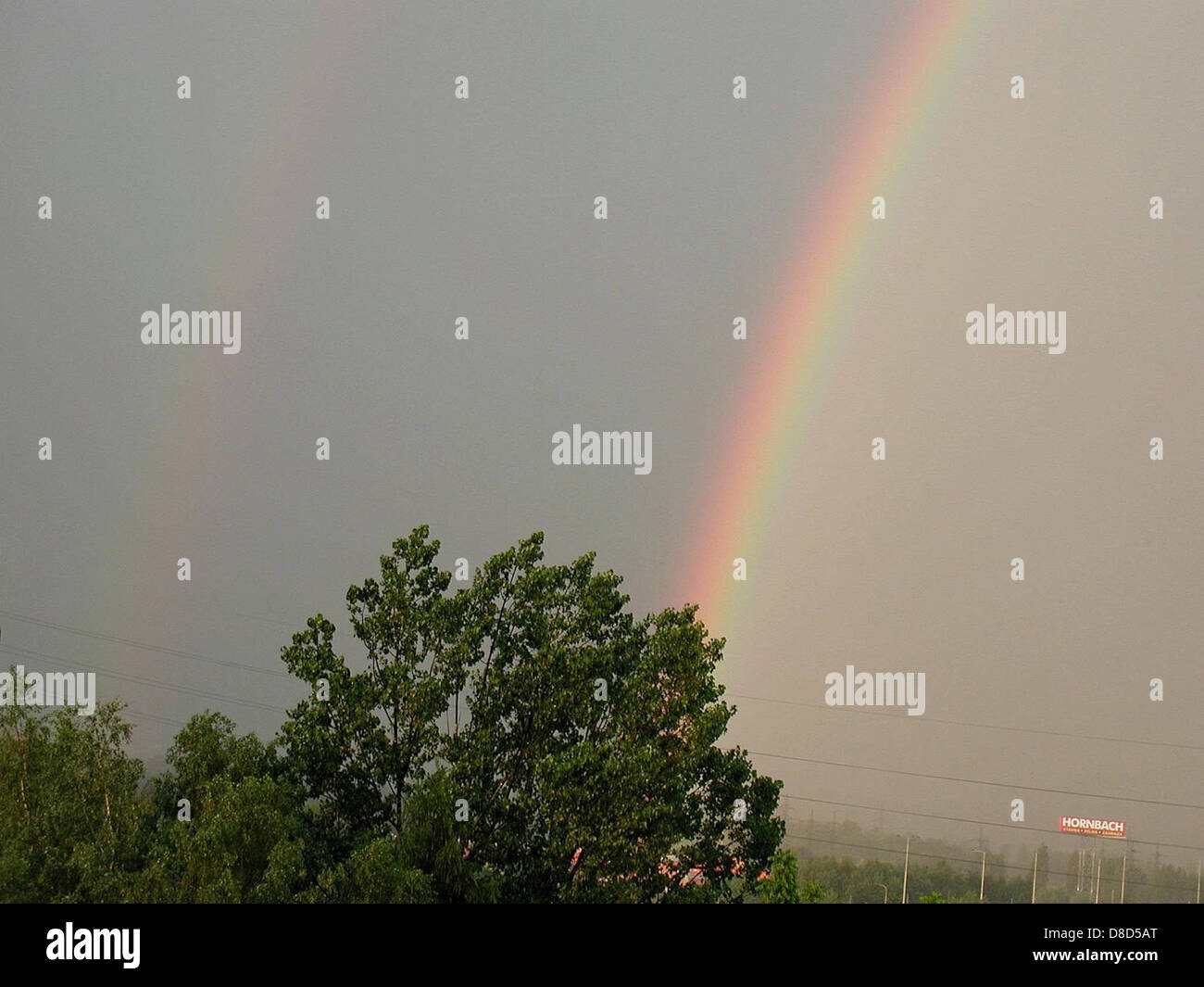 A rainbow appears in a white sky, offering a striking contrast between ...