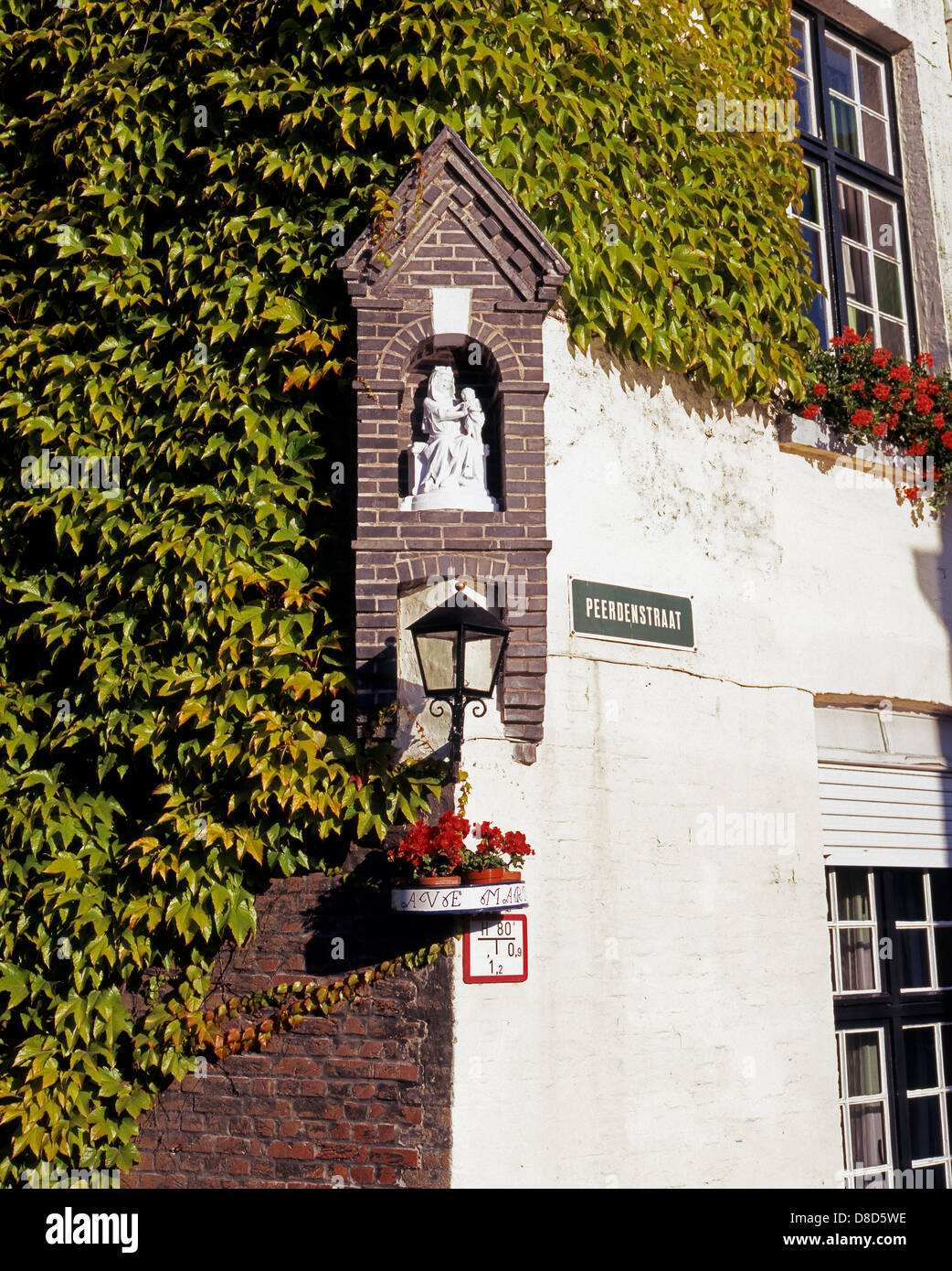 Religious figure set into the corner of a house, Bruges, West Flanders ...
