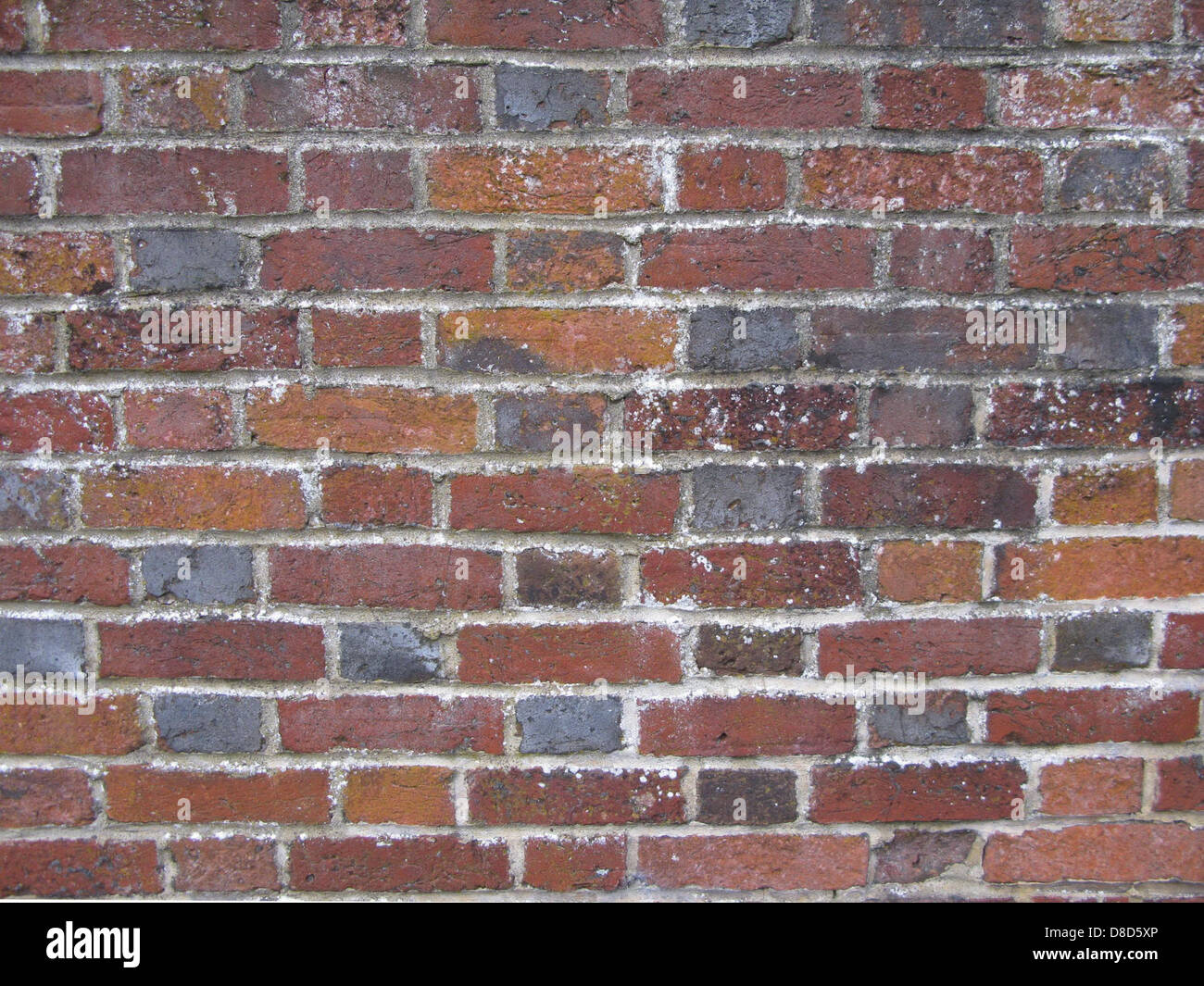 A red stone wall constructed with natural stones shows intricate ...