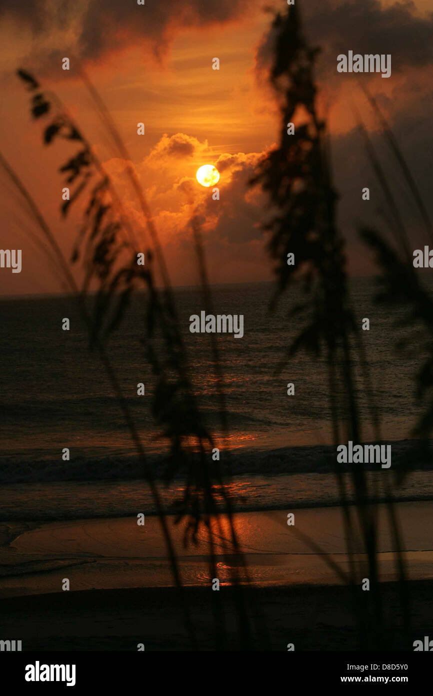 A vivid red sunrise over a wilderness landscape, with the sky glowing in shades of orange and ...