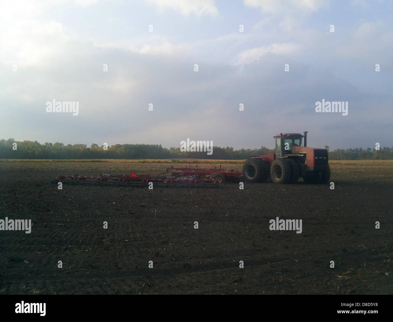 A red tractor parked in an open field, showcasing its size and utility ...