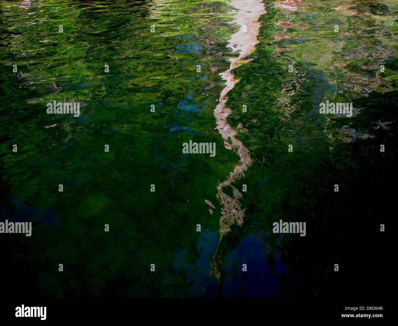 A calm water surface reflecting the surrounding landscape, creating a ...