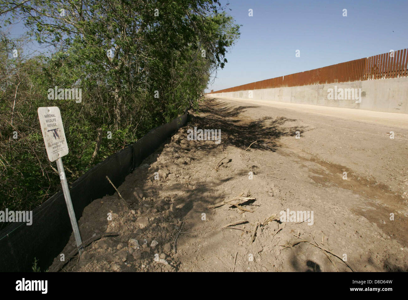 A border wall at the entrance of a wildlife refuge, accompanied by a ...
