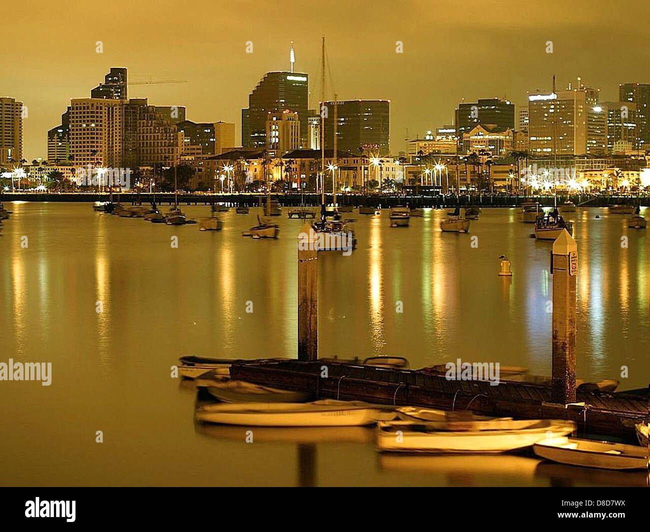 Sailboats are docked along the piers of San Diego's harbor at night ...