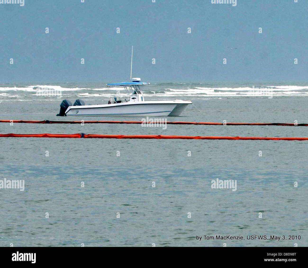 Small boat at sea near oil spill booms Stock Photo - Alamy