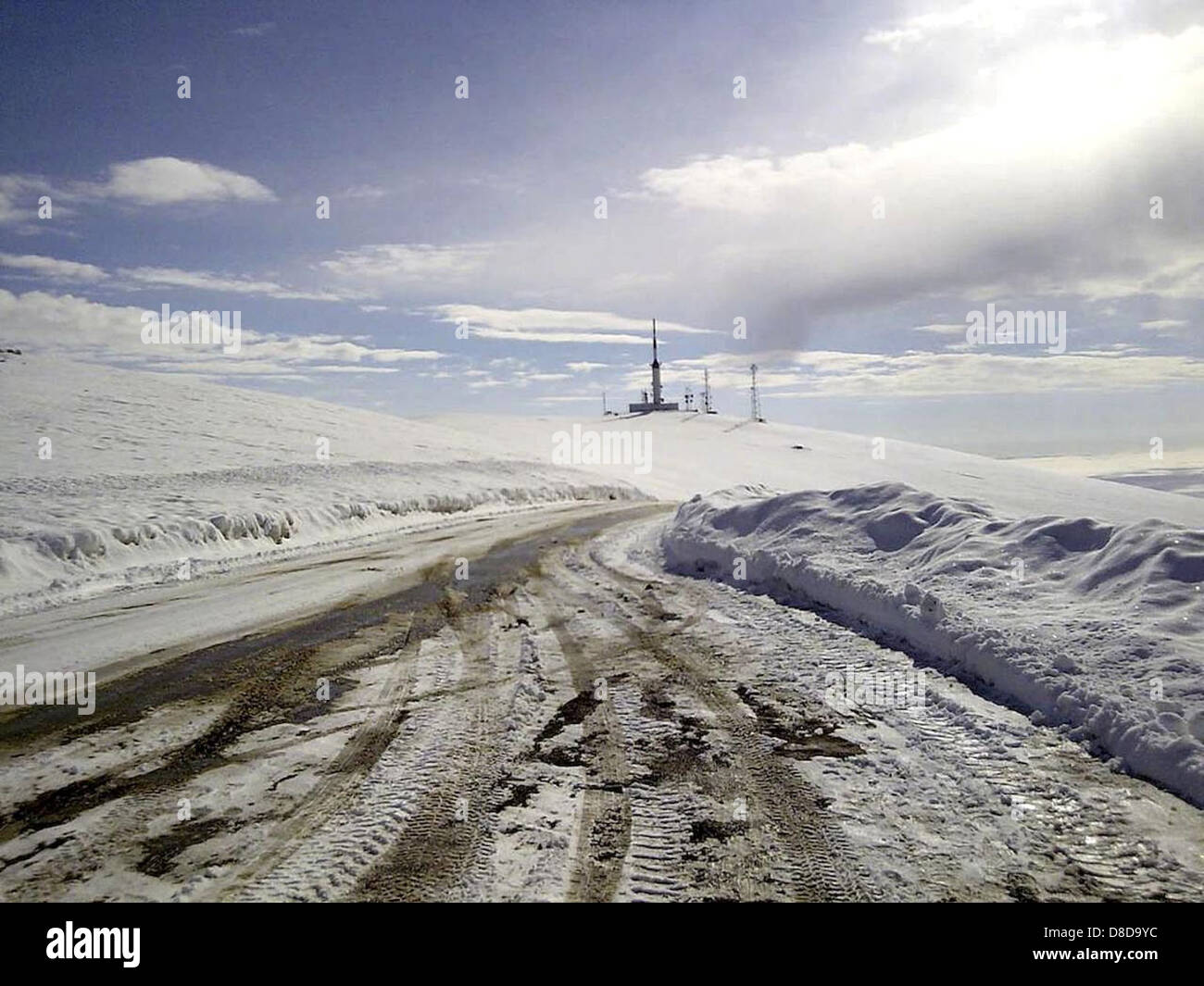 A snowy road winds through a hilly landscape, with a blanket of snow ...