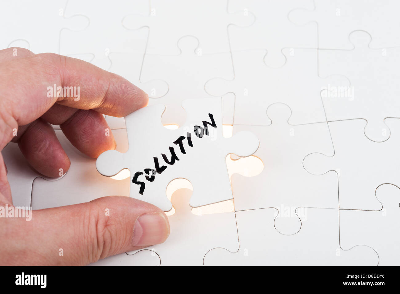 Hand holding puzzle piece which written solution word and inserting it ...