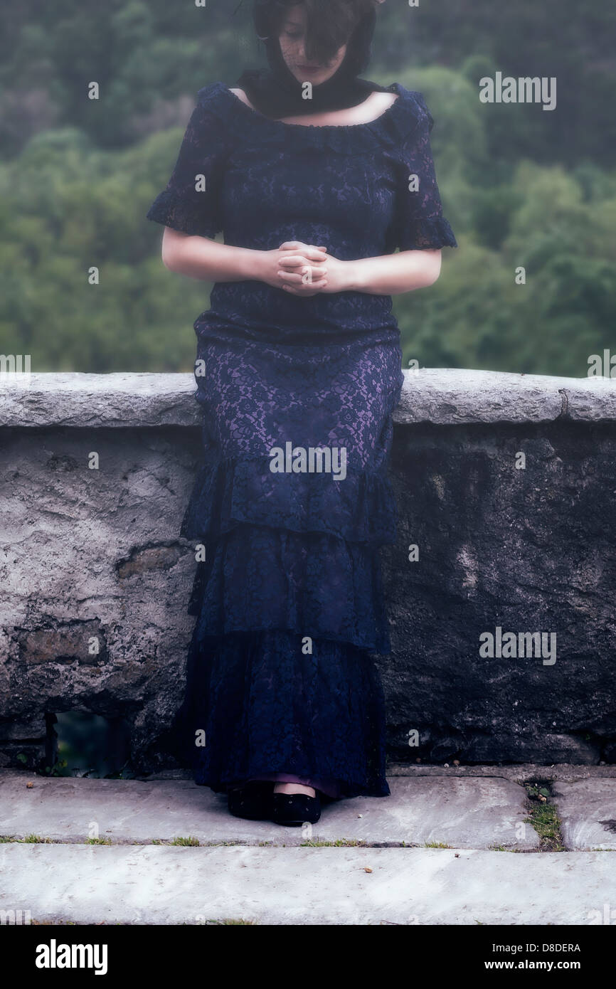 a grieving woman with veil and dark dress, praying Stock Photo - Alamy