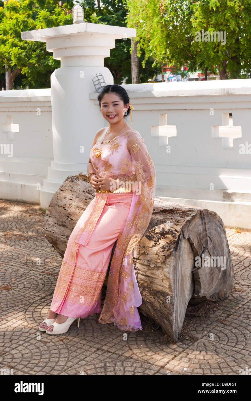 Asian Thai woman/bride in Thai wedding suit is sitting in the wood log ...