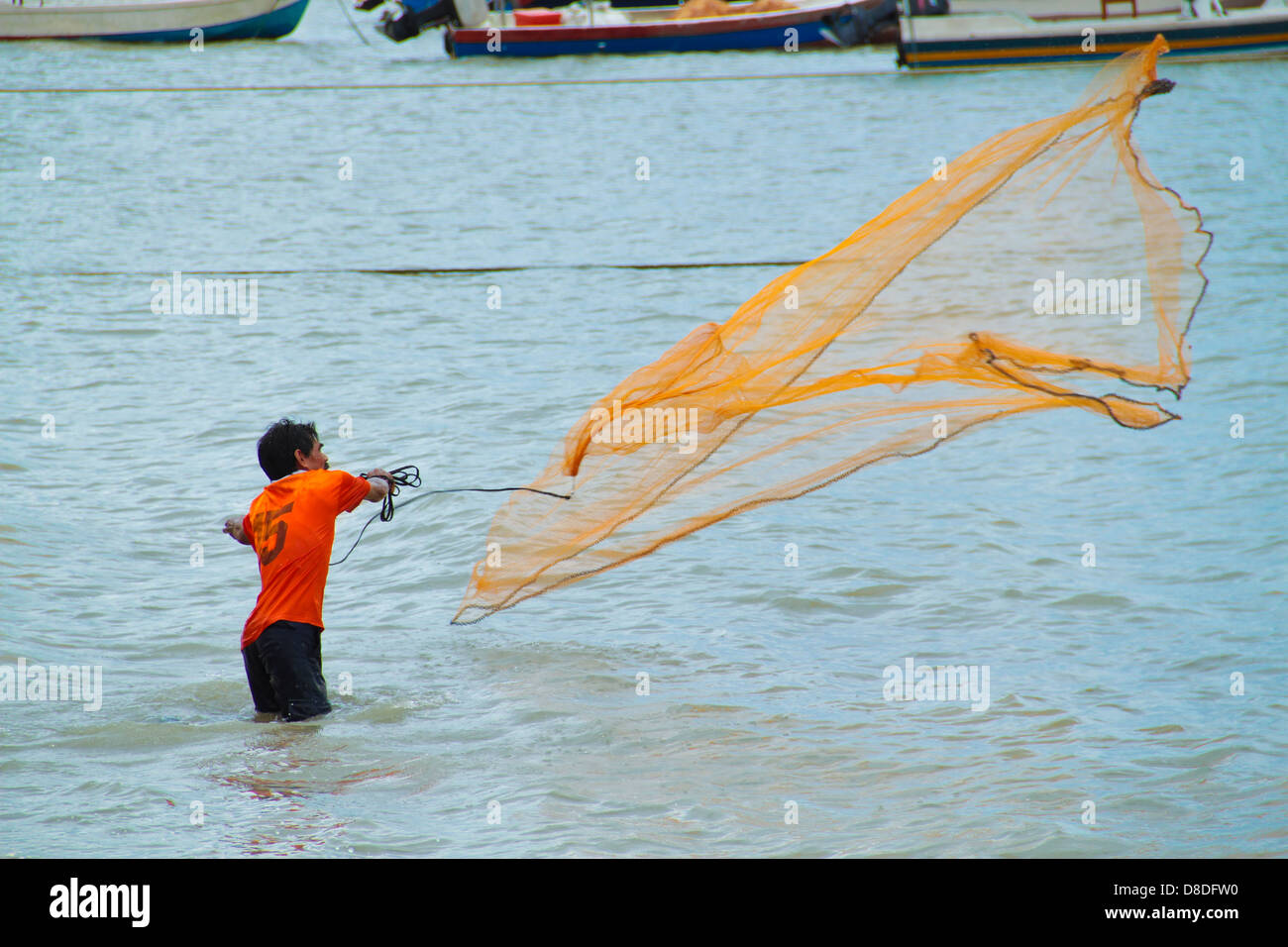 Fisherman throwing catch net Stock Photo - Alamy