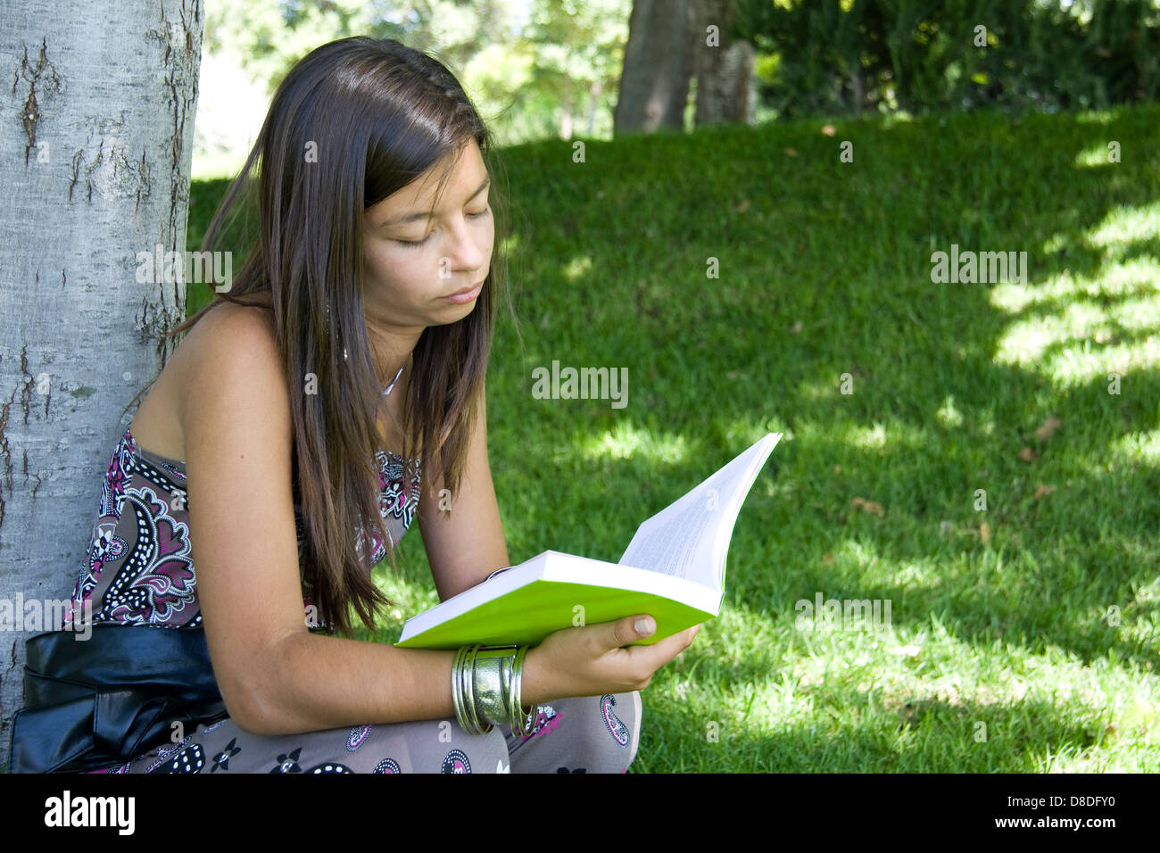 Young girl reading a book at the park Stock Photo - Alamy