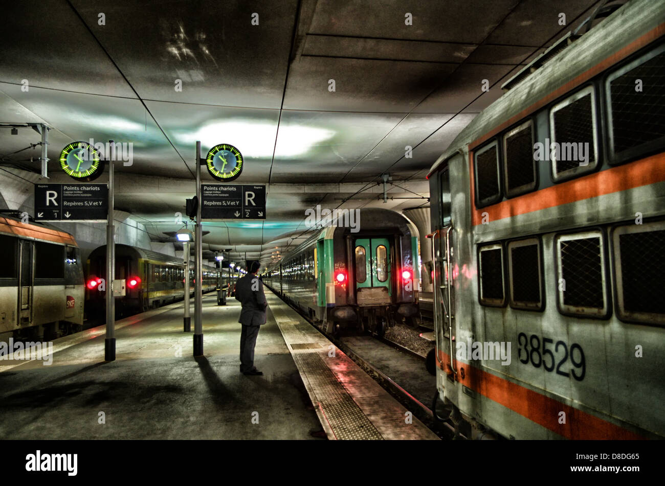 A man stands at the platform of a train depot in Paris, with several ...
