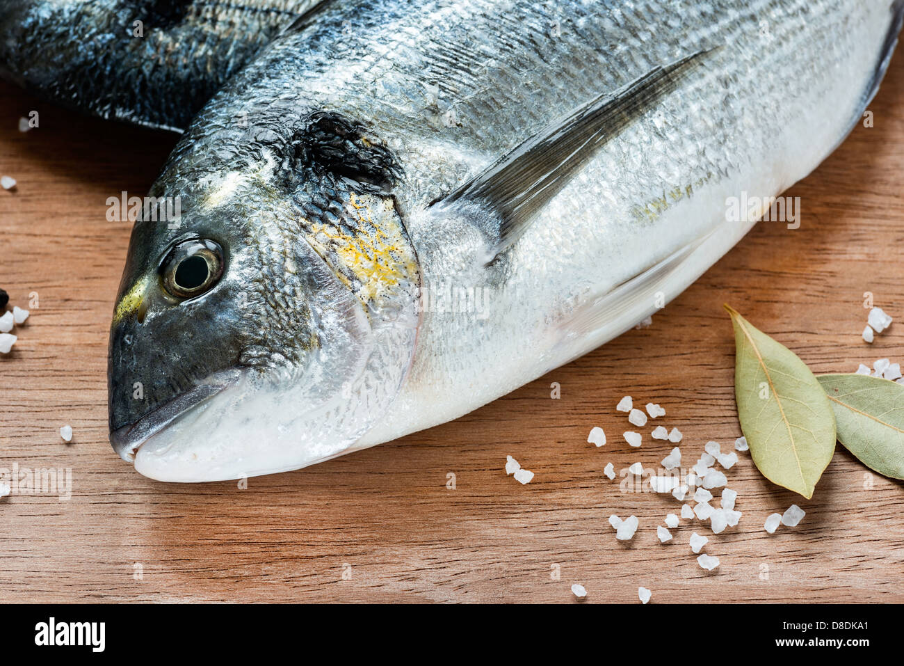 Fresh dorada fish with sea salt and bay leaf over wooden background ...