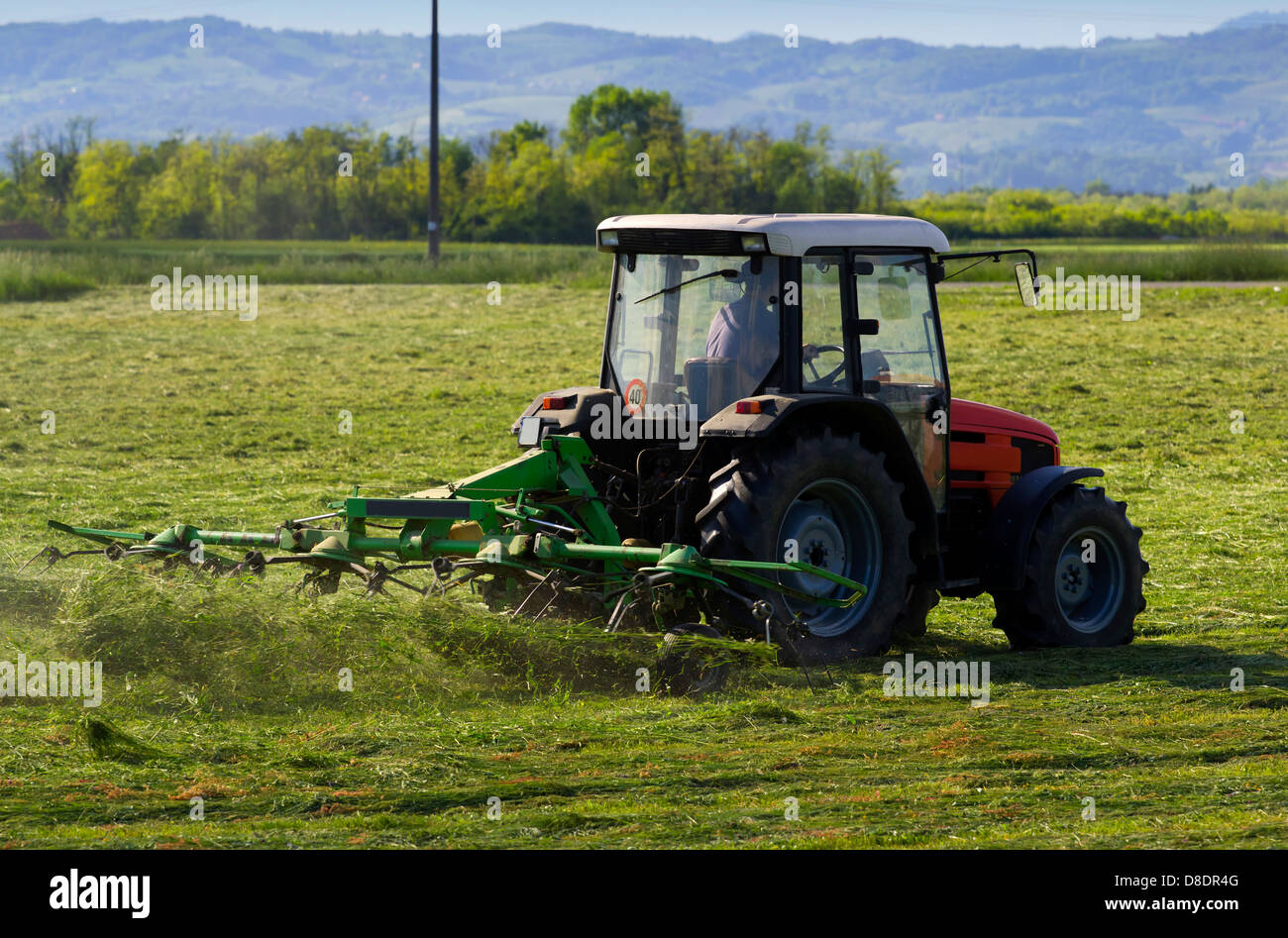 Tractor turning cut hay in a field Stock Photo - Alamy