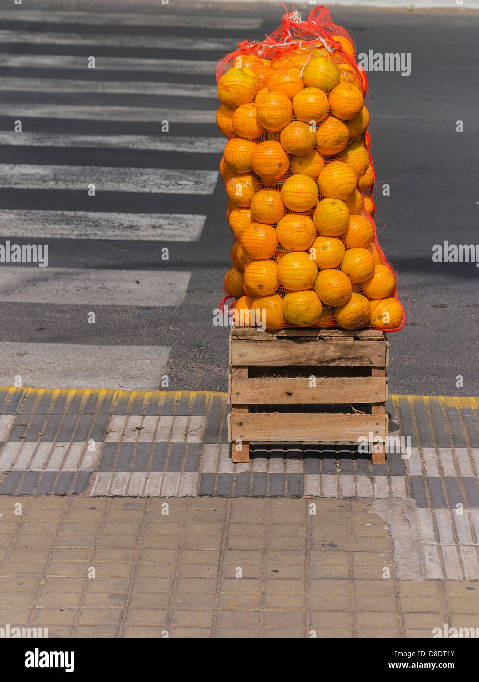 A large stack of oranges in a nylon netting bag placed on a wooden ...