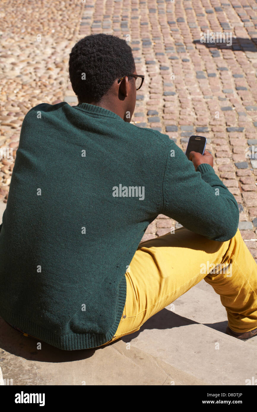 man sat on steps using phone at Oxford, Oxfordshire UK in May Stock ...