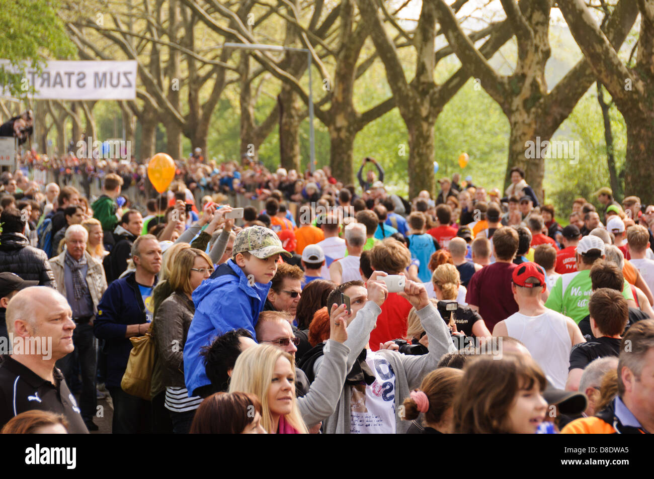 Little boy sitting on the shoulders of his father, watching a marathon ...