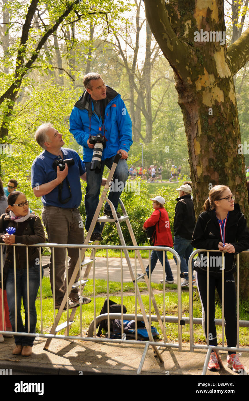 2 photographers with DSLR on a ladder, 2 female teenagers behind the ...