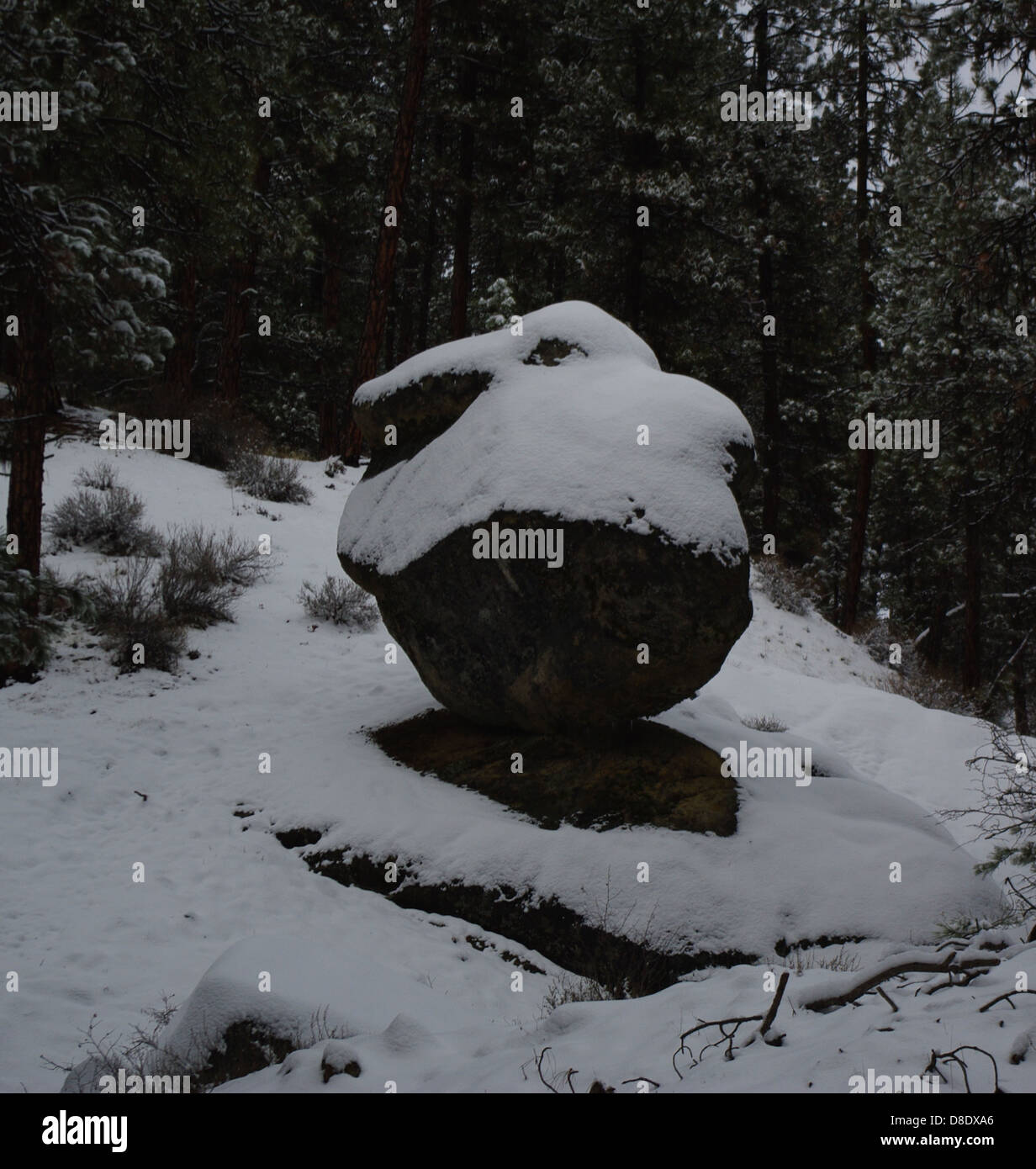 Large round boulder covered in snow sitting on rock platform in middle ...