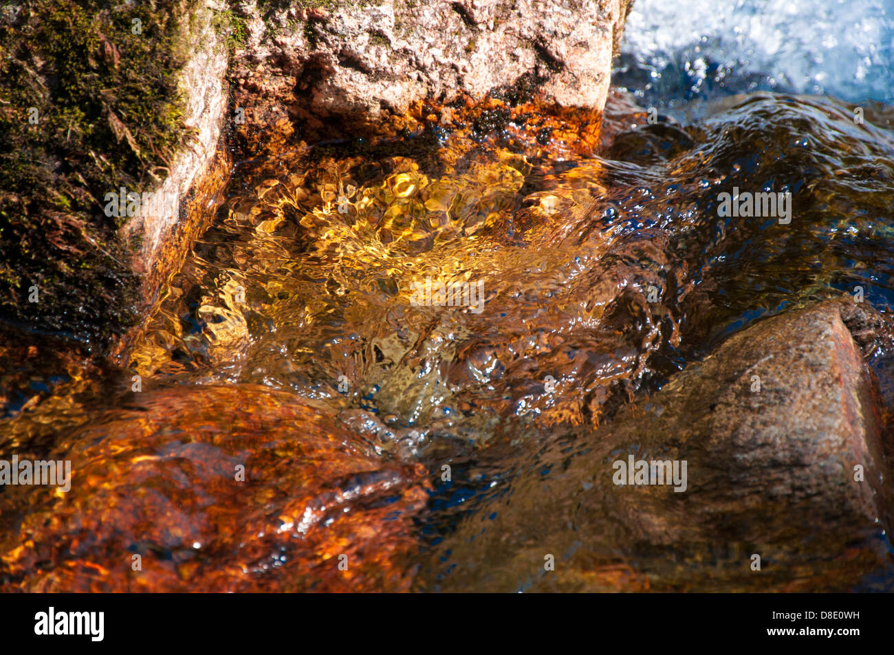 Crystal clear water flowing over golden rocks Stock Photo - Alamy