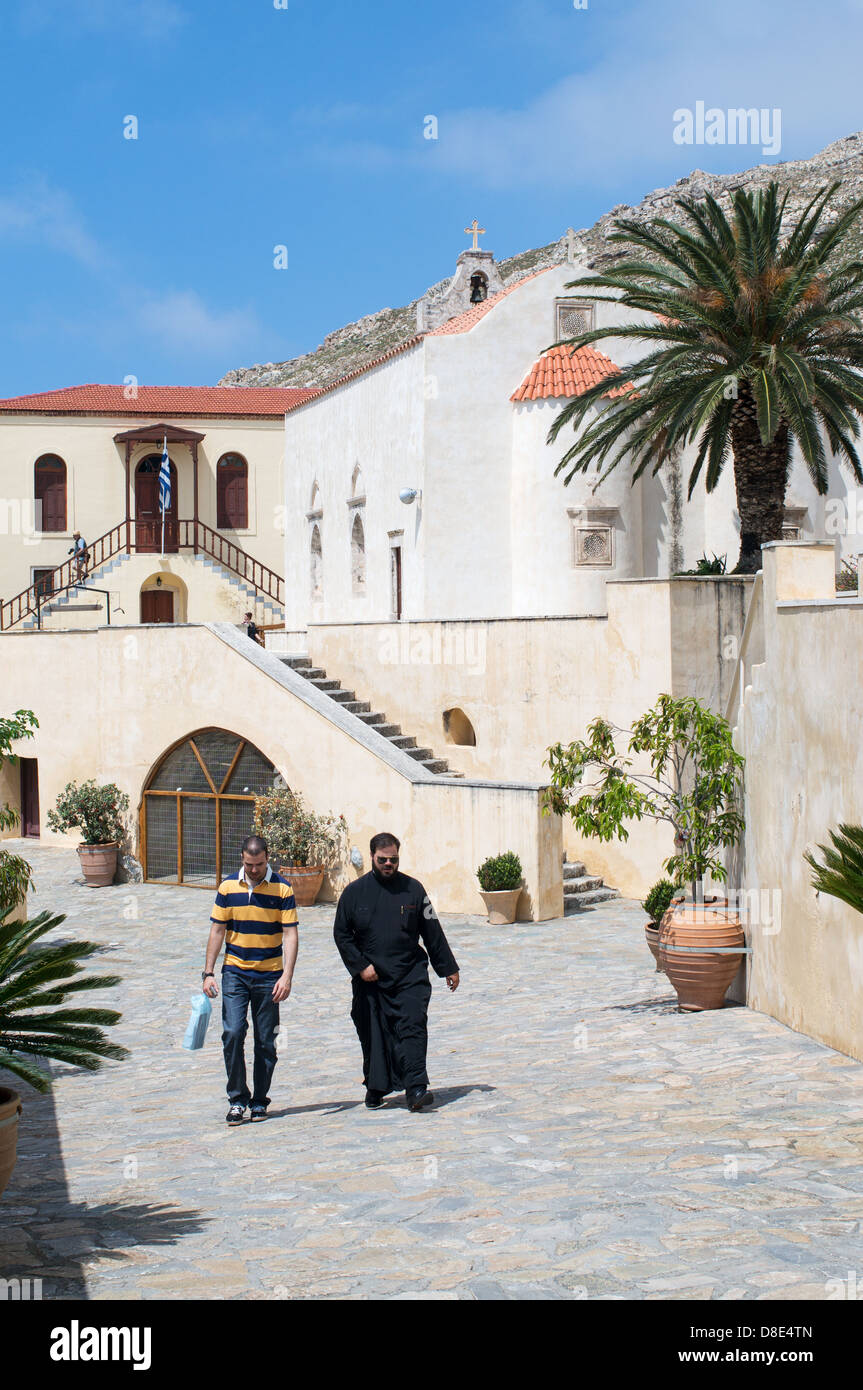 A Greek orthodox priest an layman walk through the grounds of Preveli ...