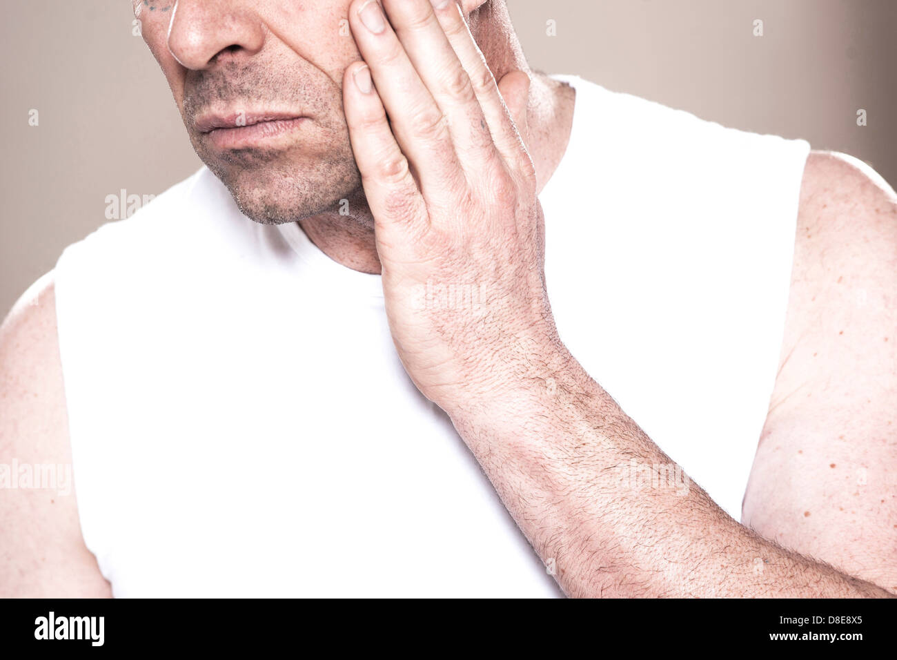 Serious man touching his cheek, close-up Stock Photo - Alamy