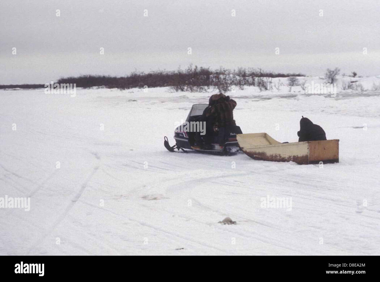 A snowmobile towing a boat across a snow-covered landscape, a practical ...