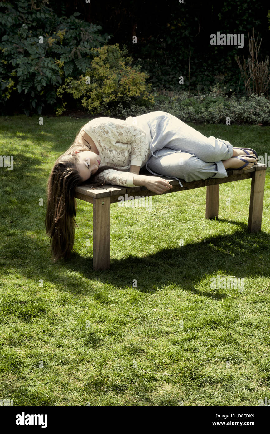 Woman Lying on Garden Bench Stock Photo - Alamy