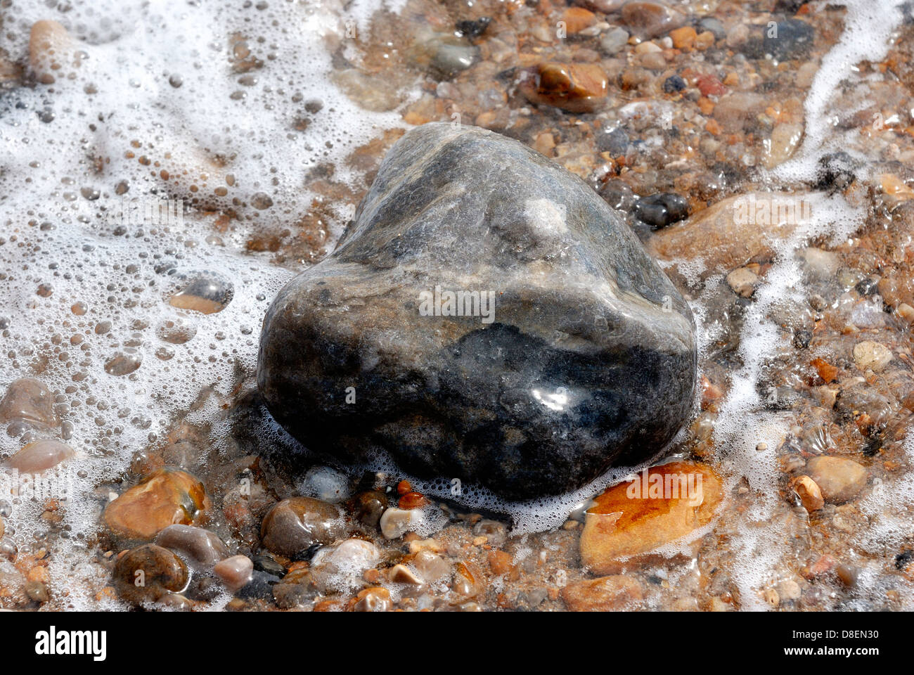 Pebbles on a beach being washed by the waves england uk Stock Photo - Alamy