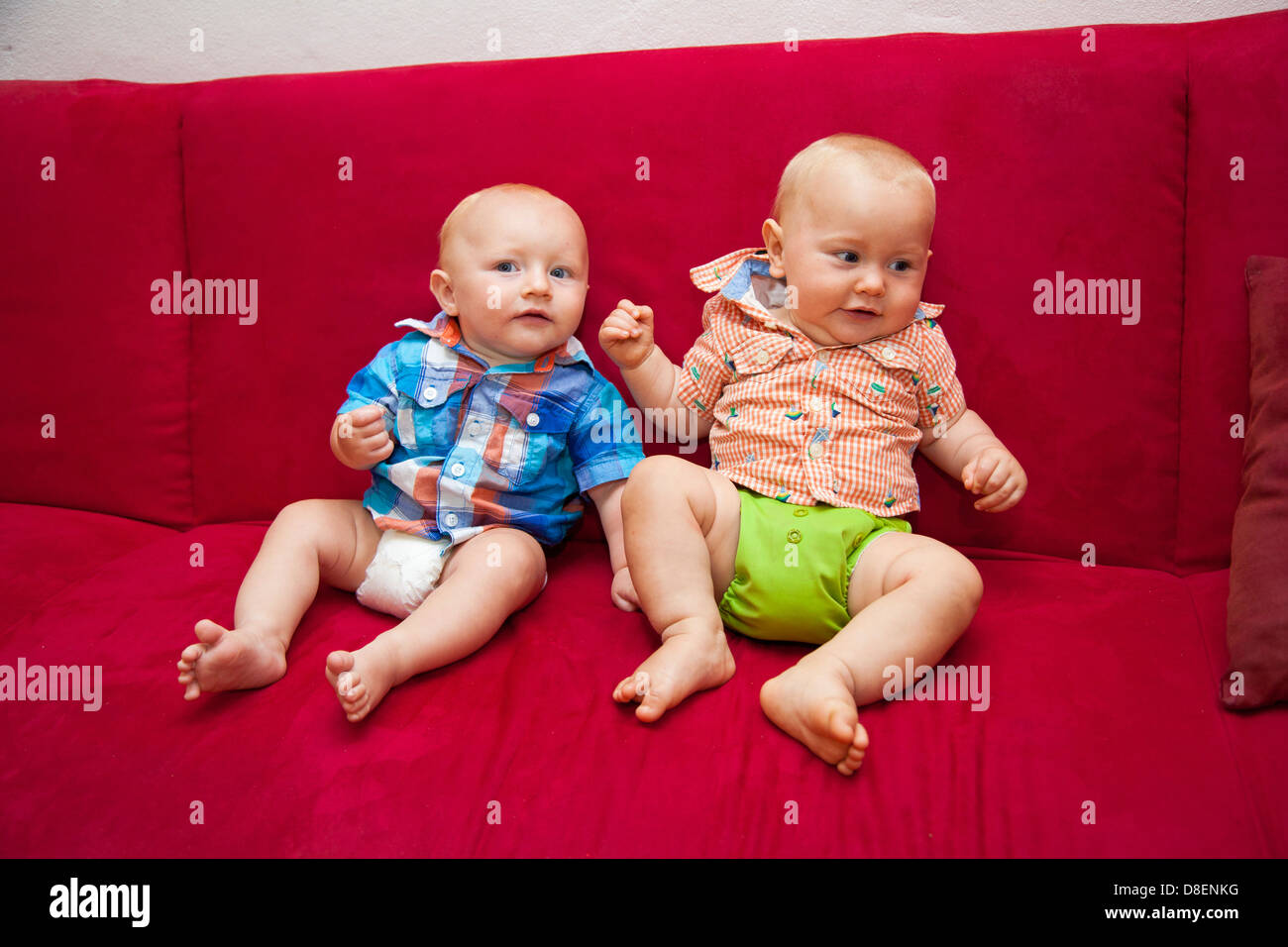 Two babies on red sofa Stock Photo - Alamy