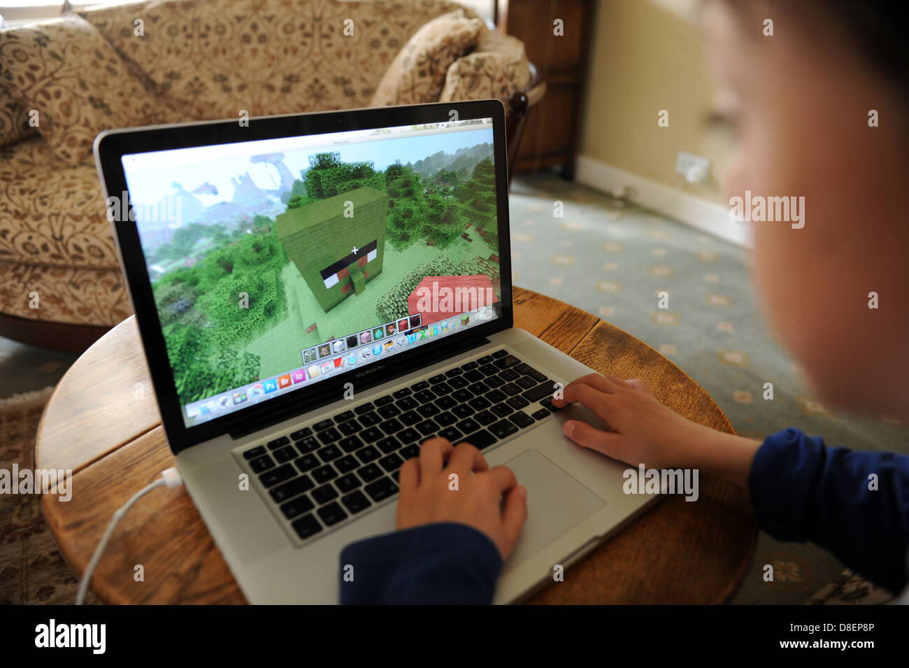 8 year old boy playing on Minecraft on an Apple lmac book pro laptop ...