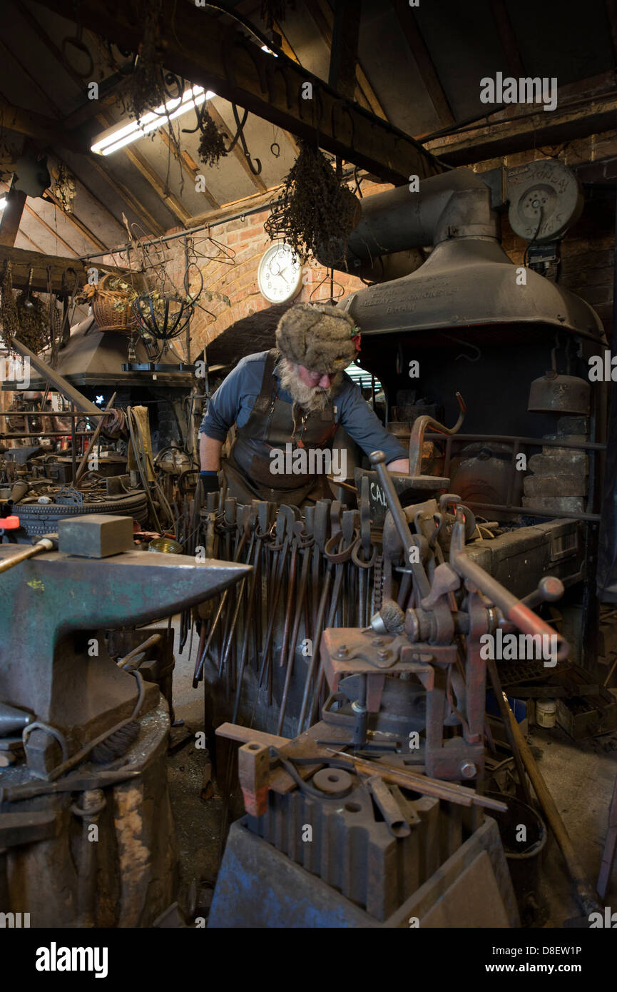 Blacksmith leaning over forge fire pit Stock Photo - Alamy