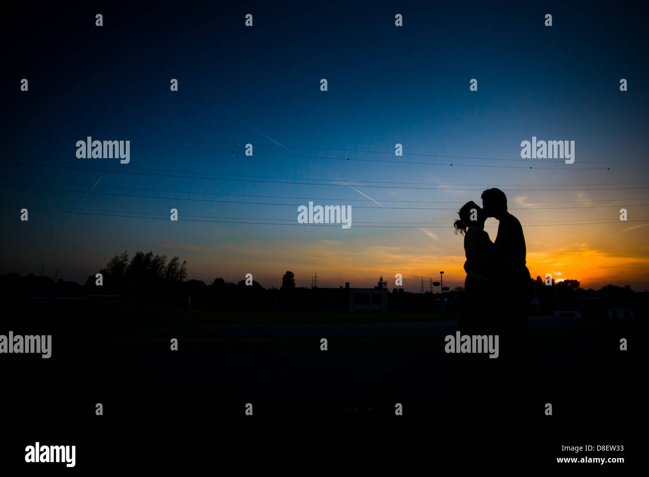 Photo of silhouettes of a loving couple kissing and hugging before a ...