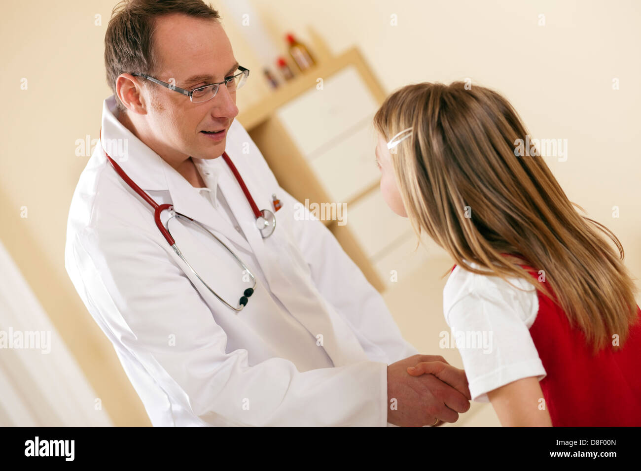 Doctor - Pediatrician - with a child patient in his practice, both are ...