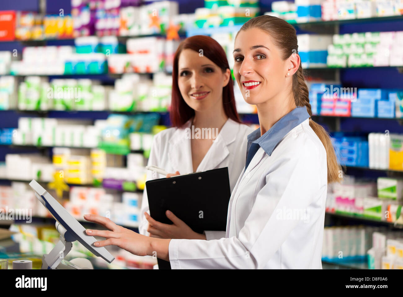 Pharmacist with female assistant in pharmacy standing at the cashpoint ...