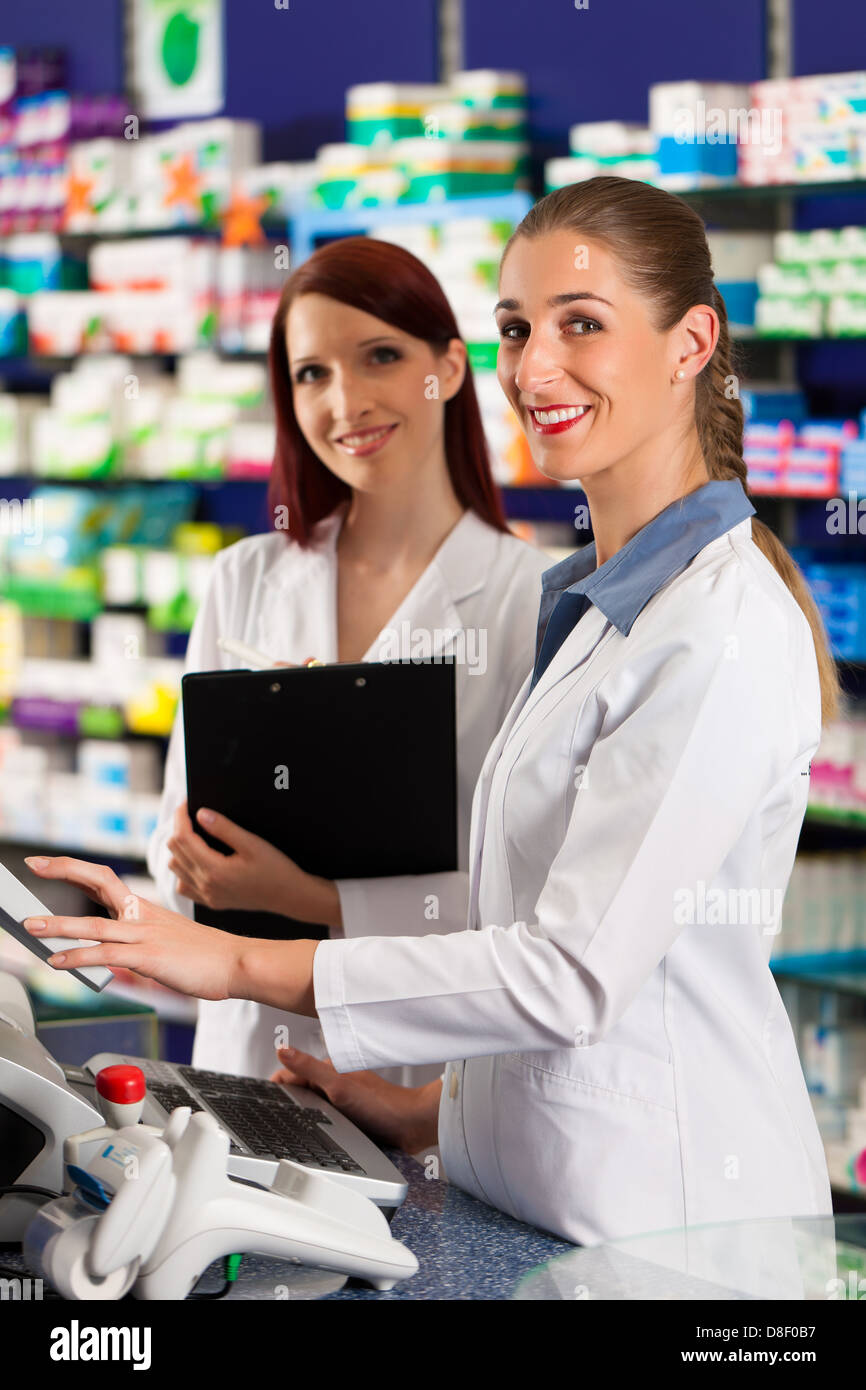 Pharmacist with female assistant in pharmacy standing at the cashpoint ...