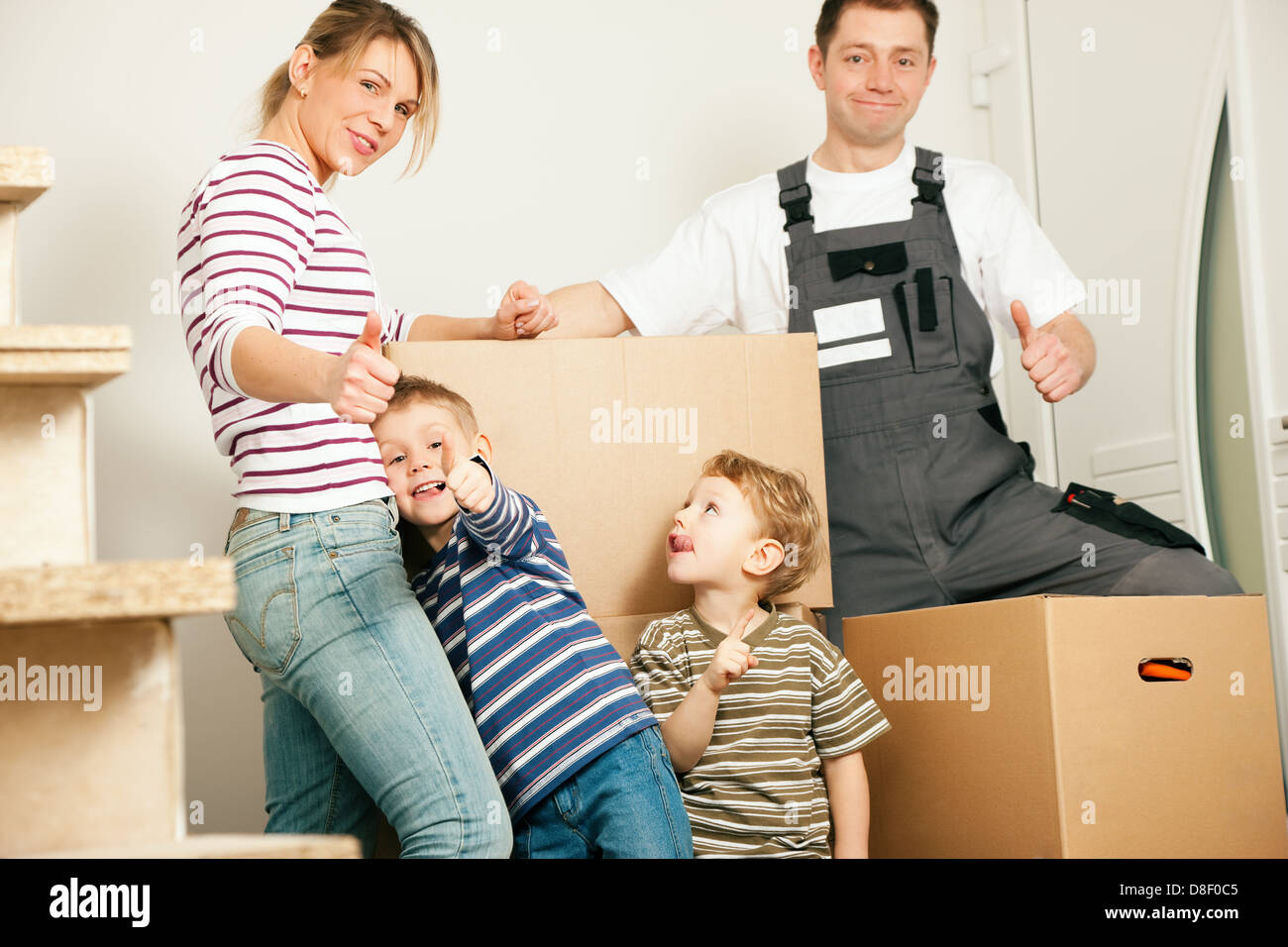 Family moving in their new house. They are standing in front of a stack ...
