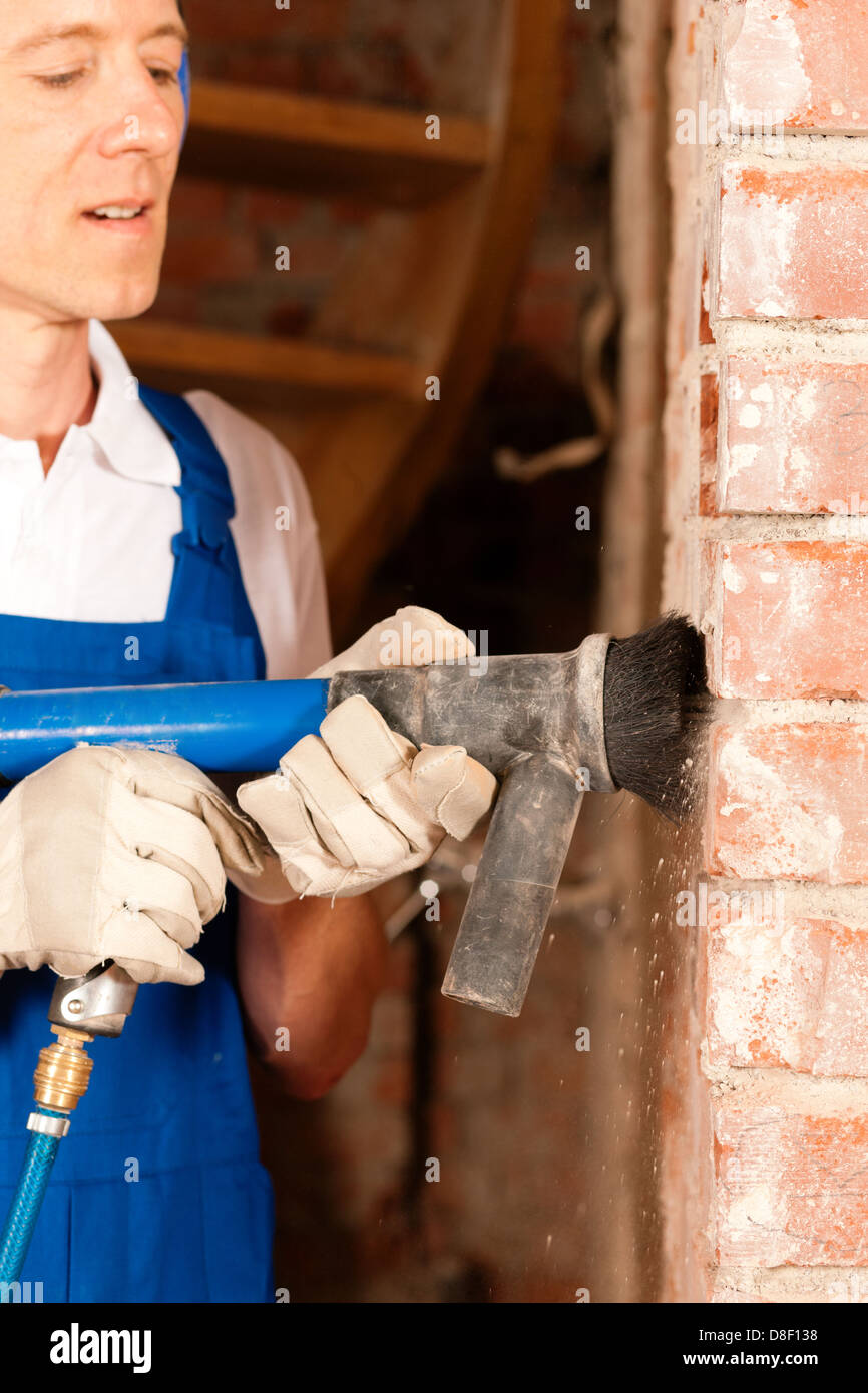 Construction worker removing the plaster from a brick wall in the ...