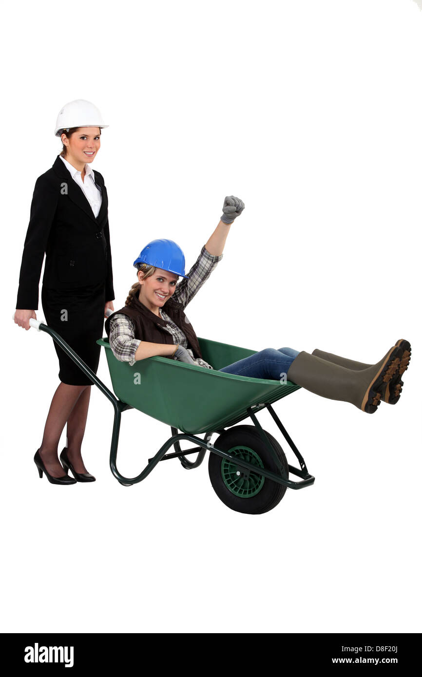 Architect pushing her colleague in wheelbarrow Stock Photo - Alamy