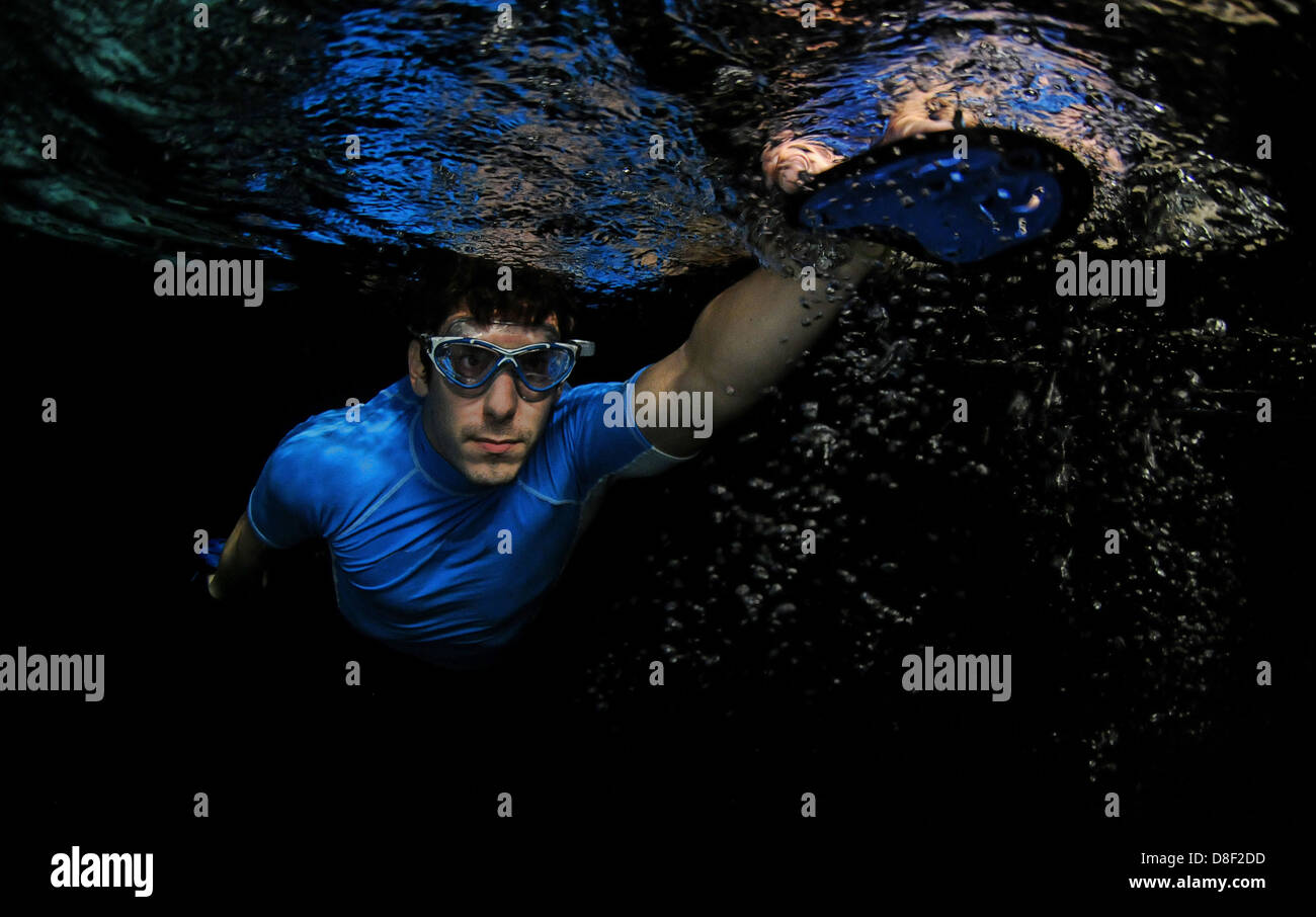 Man exercising and swimming underwater in pool with resistance swimming ...