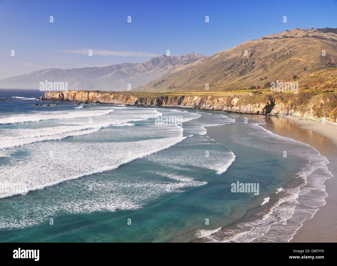 A gentle stretch of beach with surf rolling up wave after wave to run ...