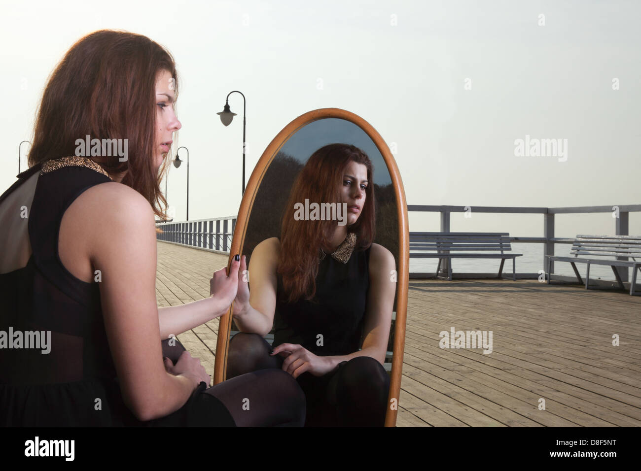 thoughtful young woman looks at the reflection in the mirror - solitude ...