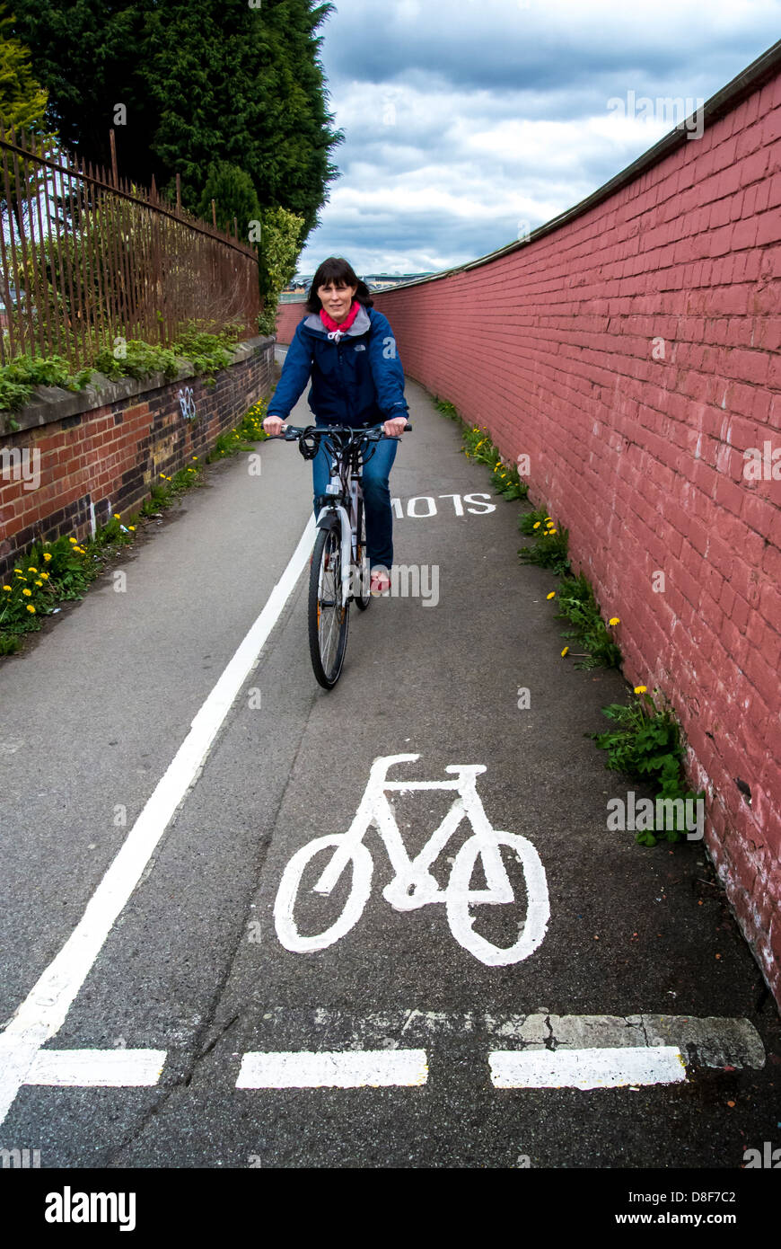 Mature caucasian woman riding a bike on narrow cycle path Stock Photo ...