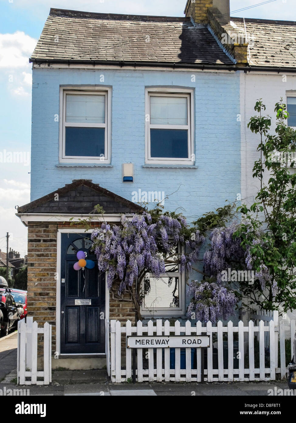 A blue Victorian cottage with wisteria creeper and white picket fence ...