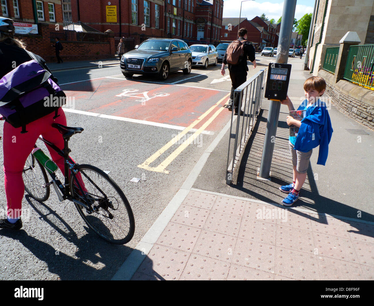 Young boy waiting at traffic lights to cross road while person on ...